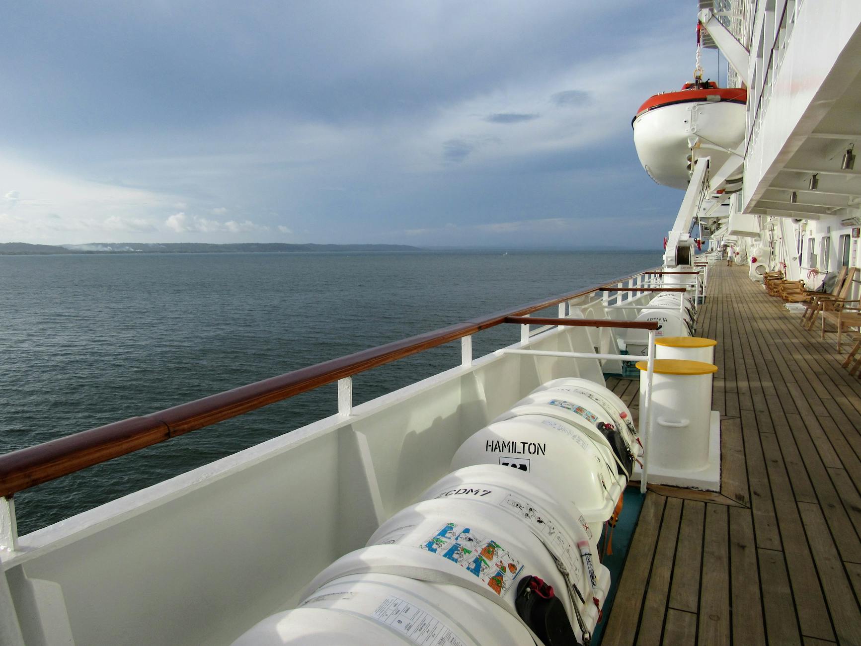 Empty cruise deck with lifeboats overlooking calm ocean horizon